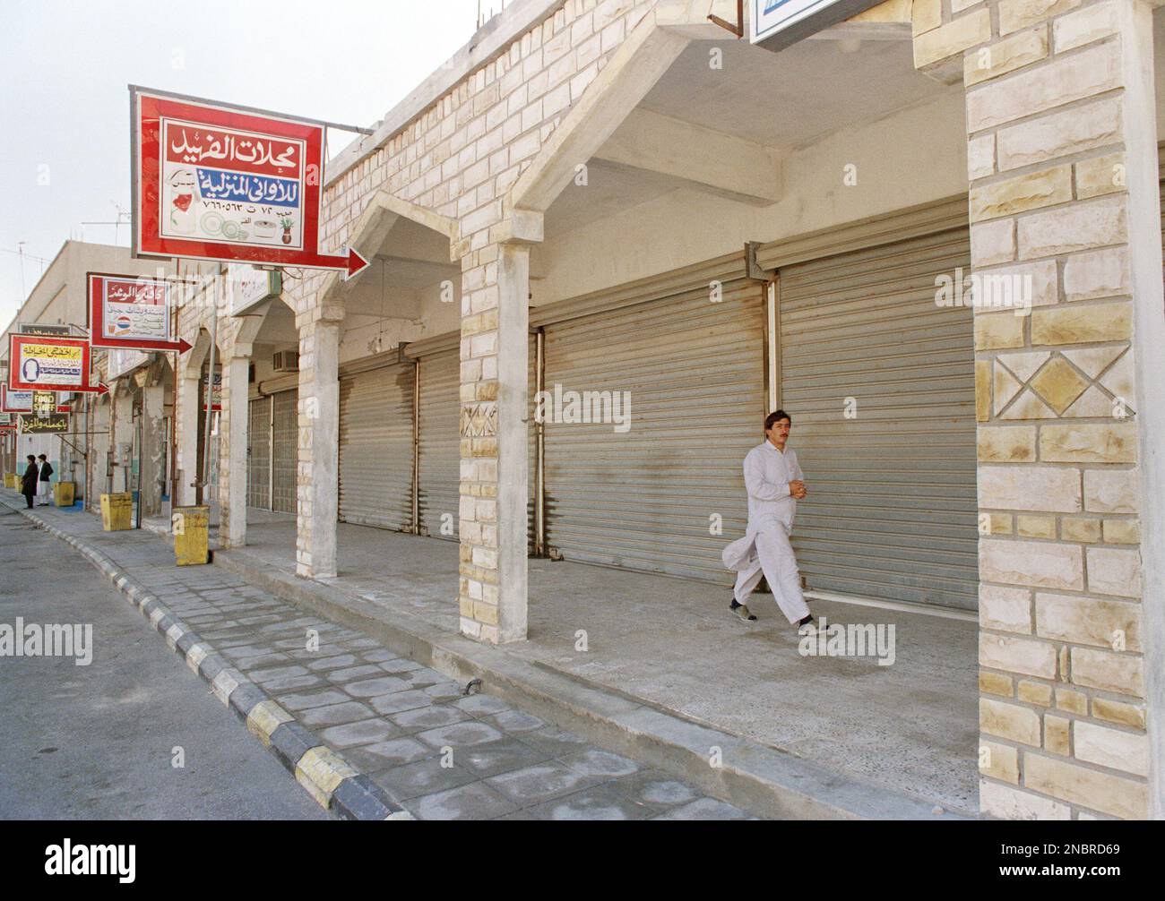 A lone worker is framed in the arches of a shopping center in the ...