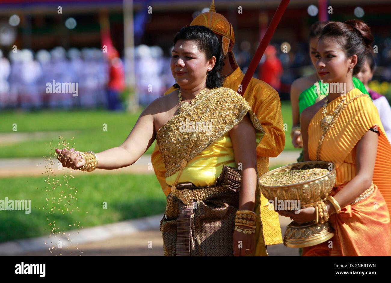 Keo Chanmony, left, throws rice seeds during an annual royal plowing ...