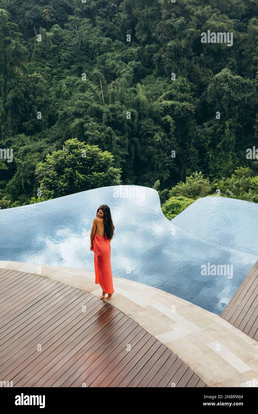 Aerial view of young female standing by swimming pool. Woman near ...
