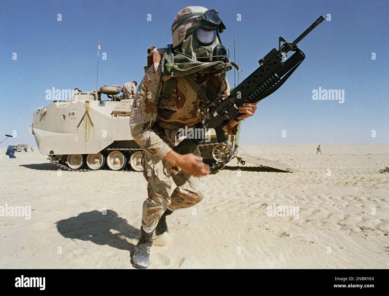 A U.S. Marine clad in a gas mask dashes from an amtrack vehicle ...