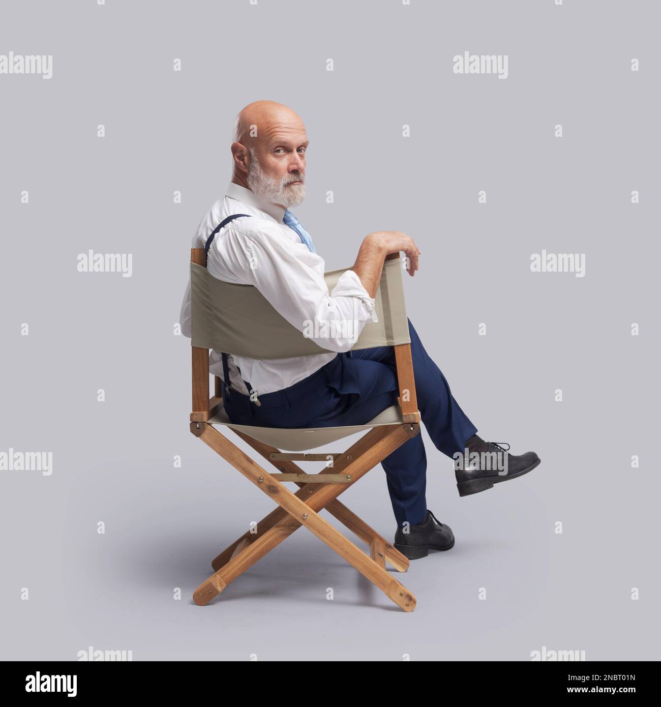Confident film director sitting on the director's chair and looking at ...