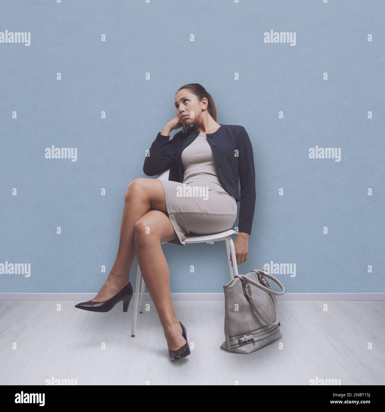 Bored young woman sitting on a chair and waiting for a job interview ...