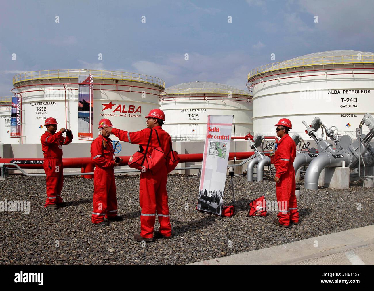 Workers gather in front of fuel tanks during the inauguration of Alba ...