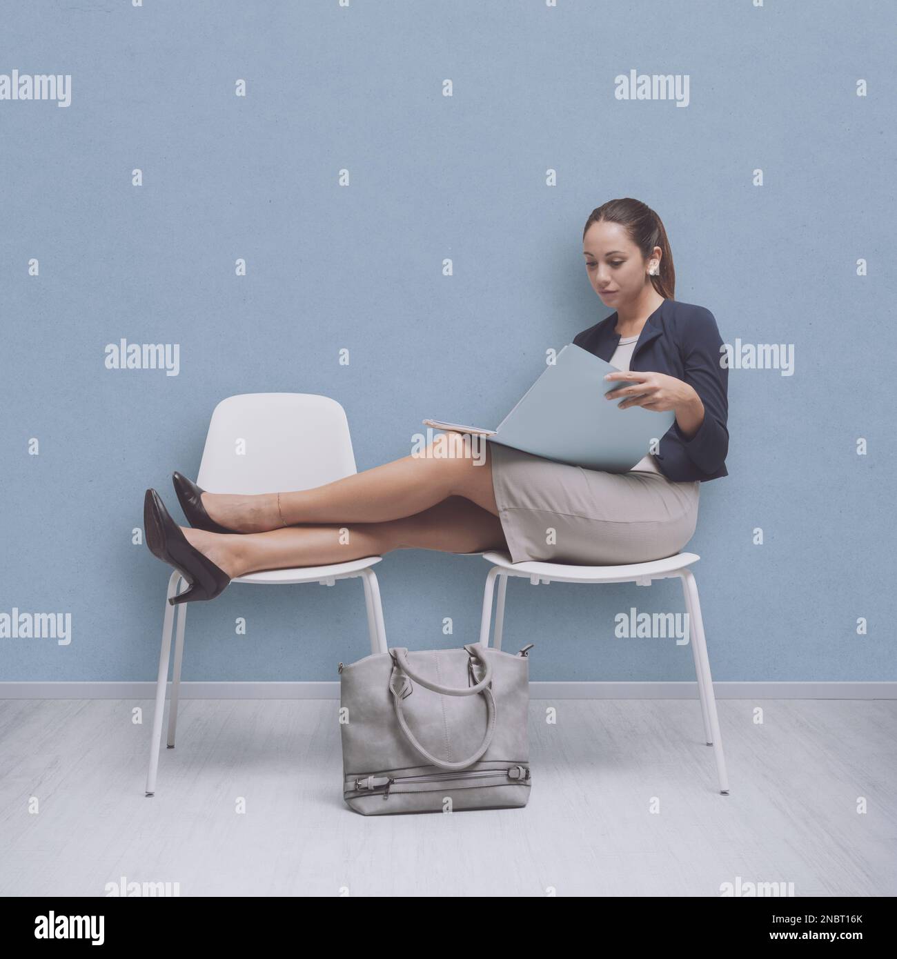 Job applicant sitting with feet up in the waiting room and checking her ...