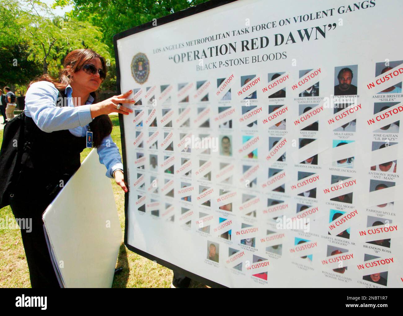 FBI agent Lourdes Arocho adjusts a poster showing faces of dozens of ...
