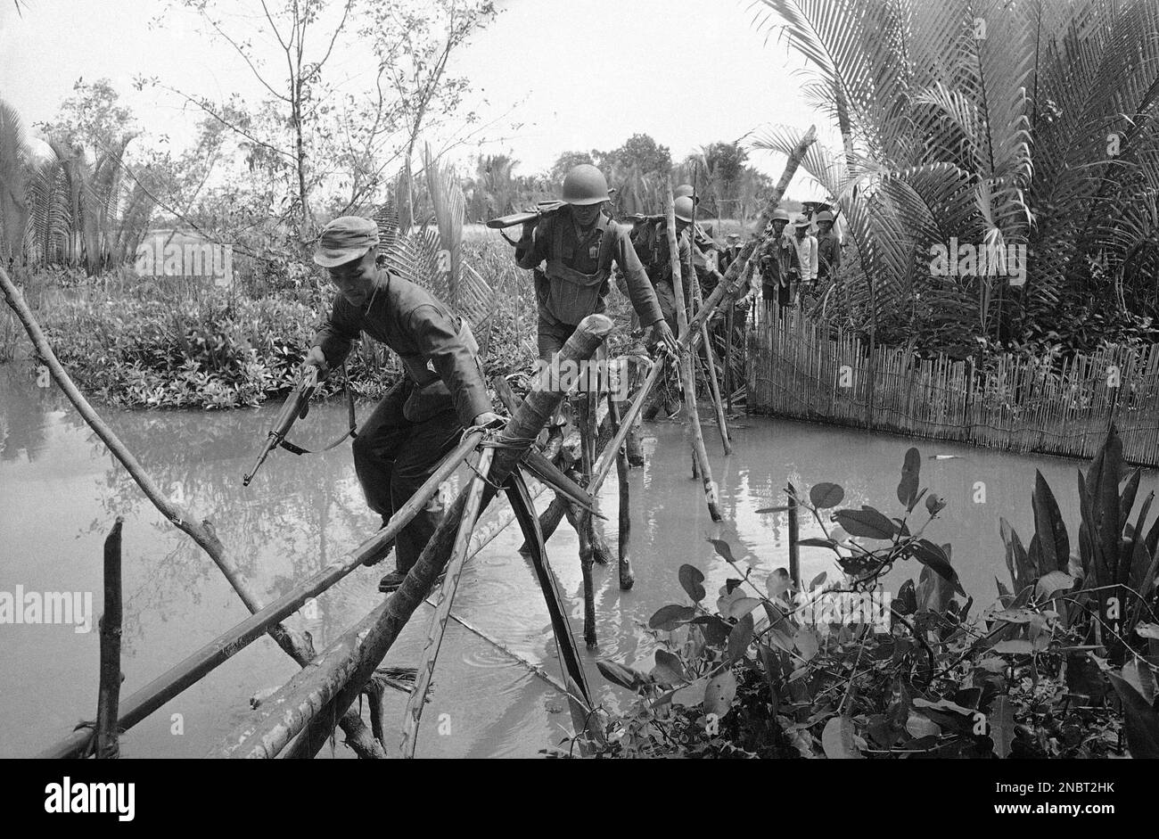 Vietnamese civil guards cross a slippery footbridge during a mopping up ...