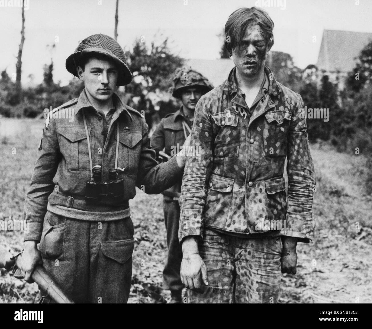 A wounded German prisoner, wearing a camouflages uniform, is escorted ...
