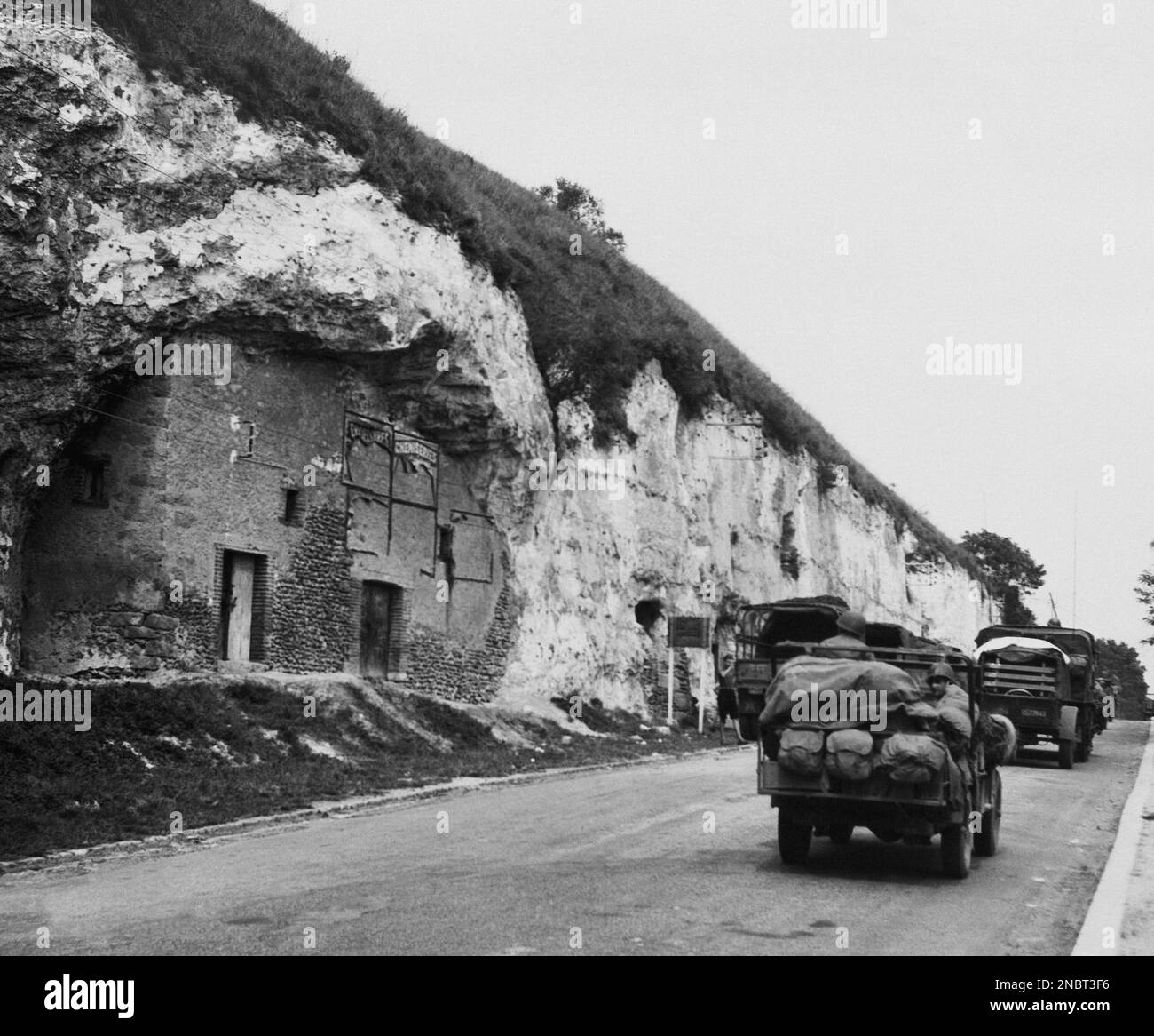 U.S. Army trucks roll past a captured German ammunition and supply dump ...
