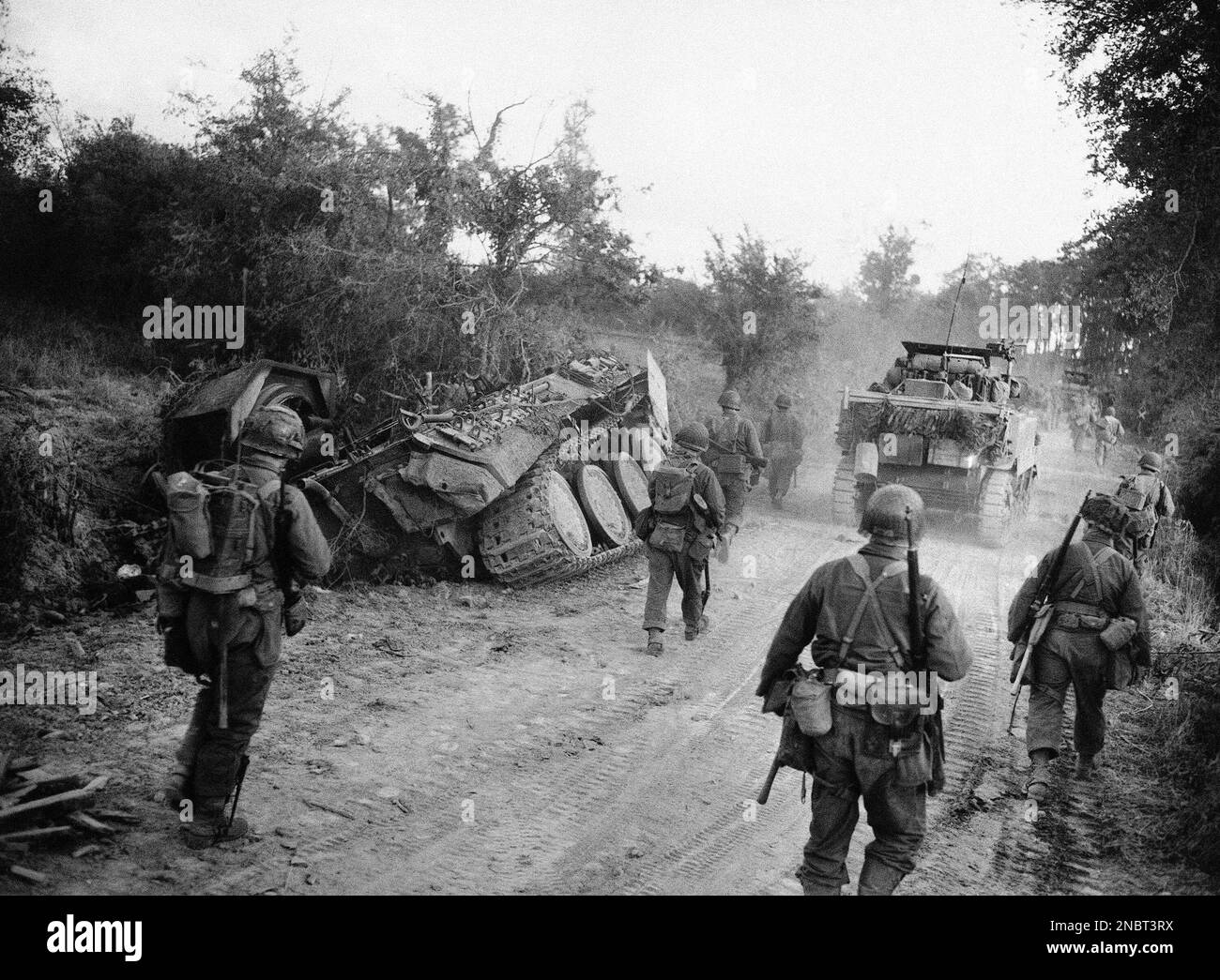 American infantry advance down a road west of St. Lo past a knocked-out ...