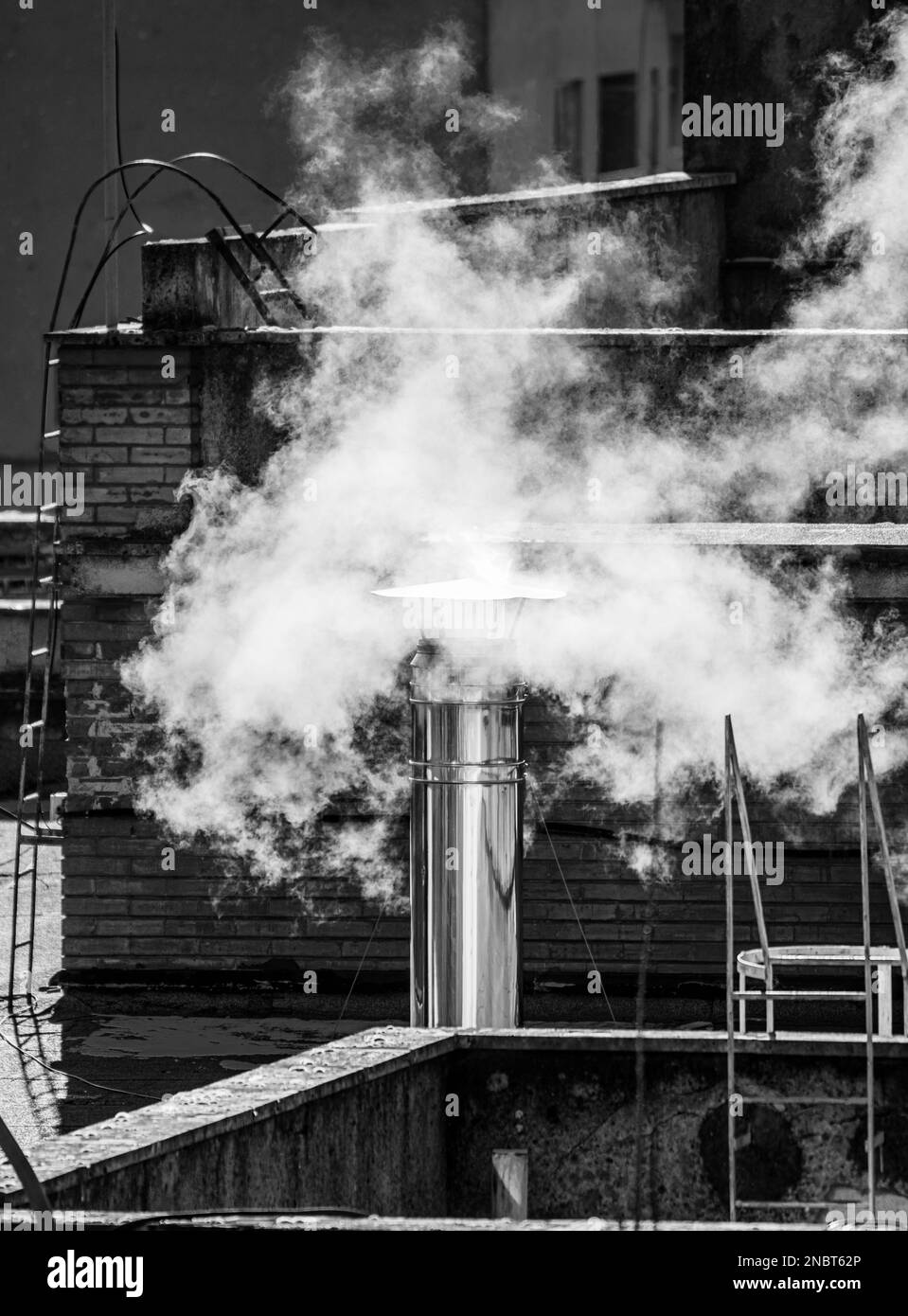 A vertical grayscale of a chimney throwing out smoke in the process of ...