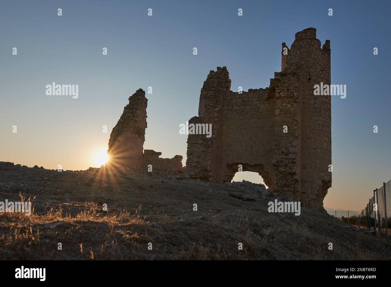 Caudilla castle in ruins in a field with sun rays at sunset in spring ...