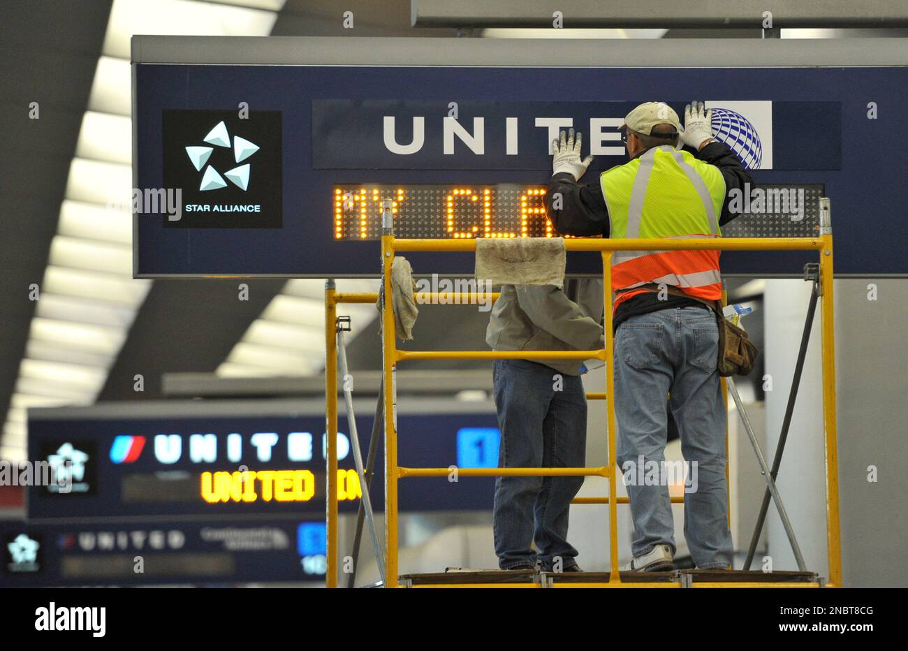 Thomas Drozd covers up the old United Airlines logo with a new sign ...