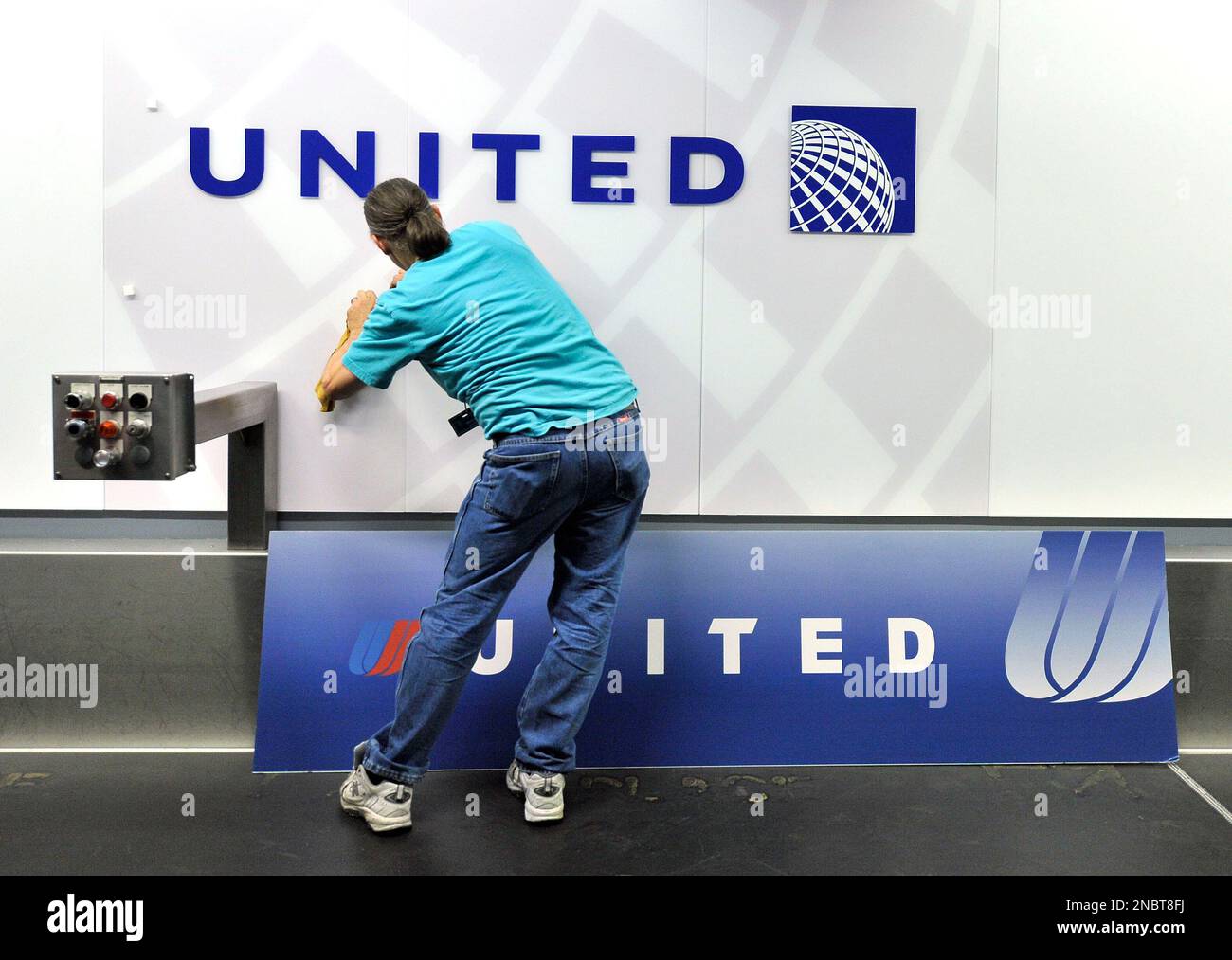 Steve Reininger removes a sign with the old United Airlines logo to ...