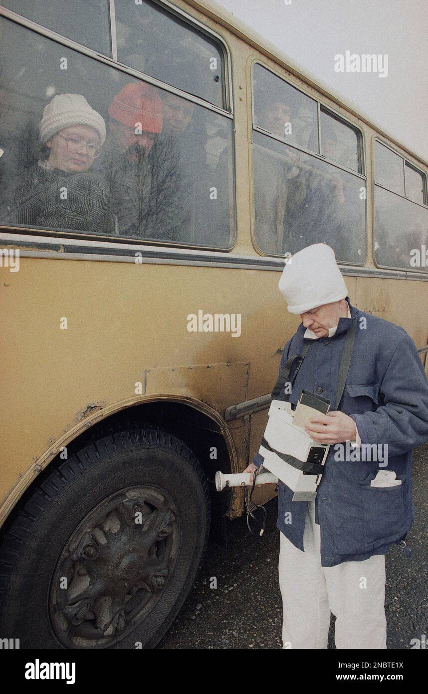 A disaster worker measures a radiation level at the wheel of a ...