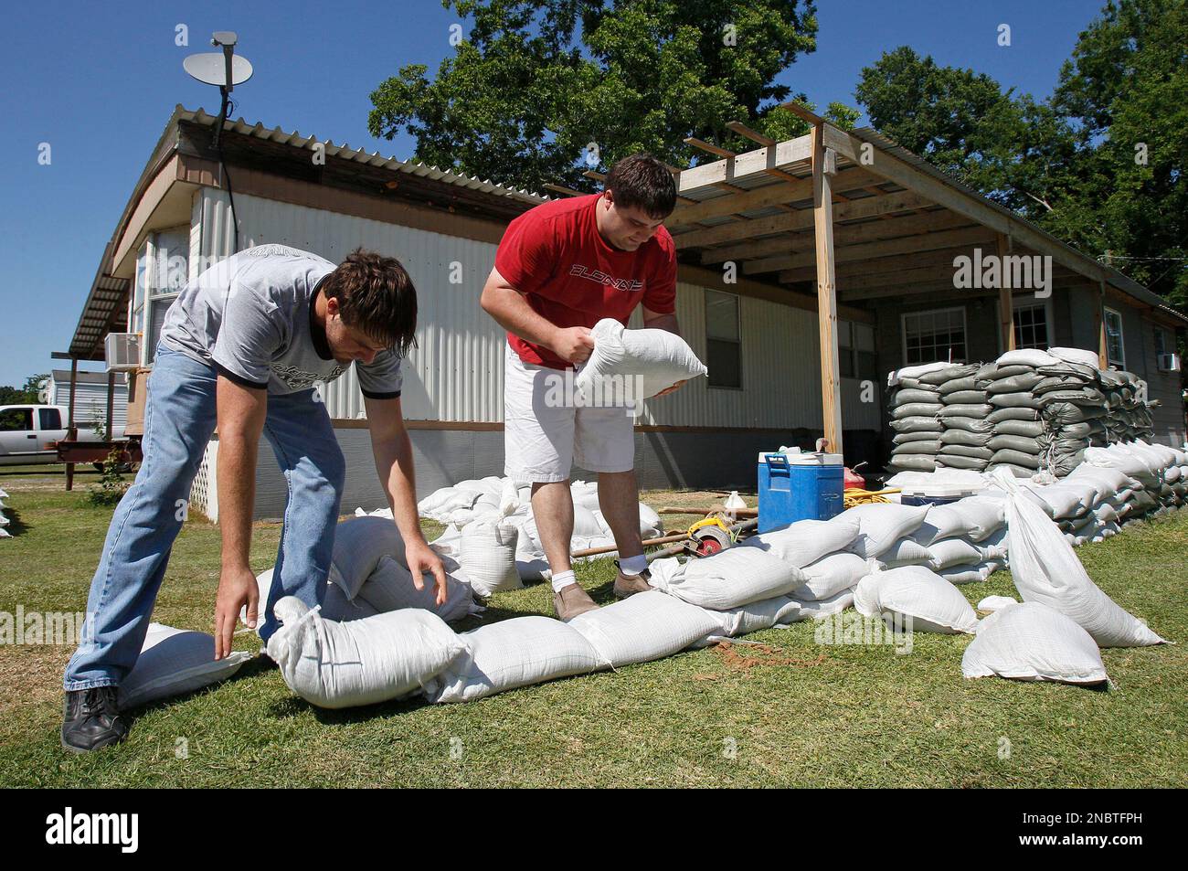 Ty Fontenot, left, and his brother Aron build a wall of sand bags ...
