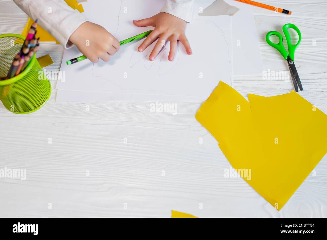 The child circles his hand with a pencil. The little girl learns to ...