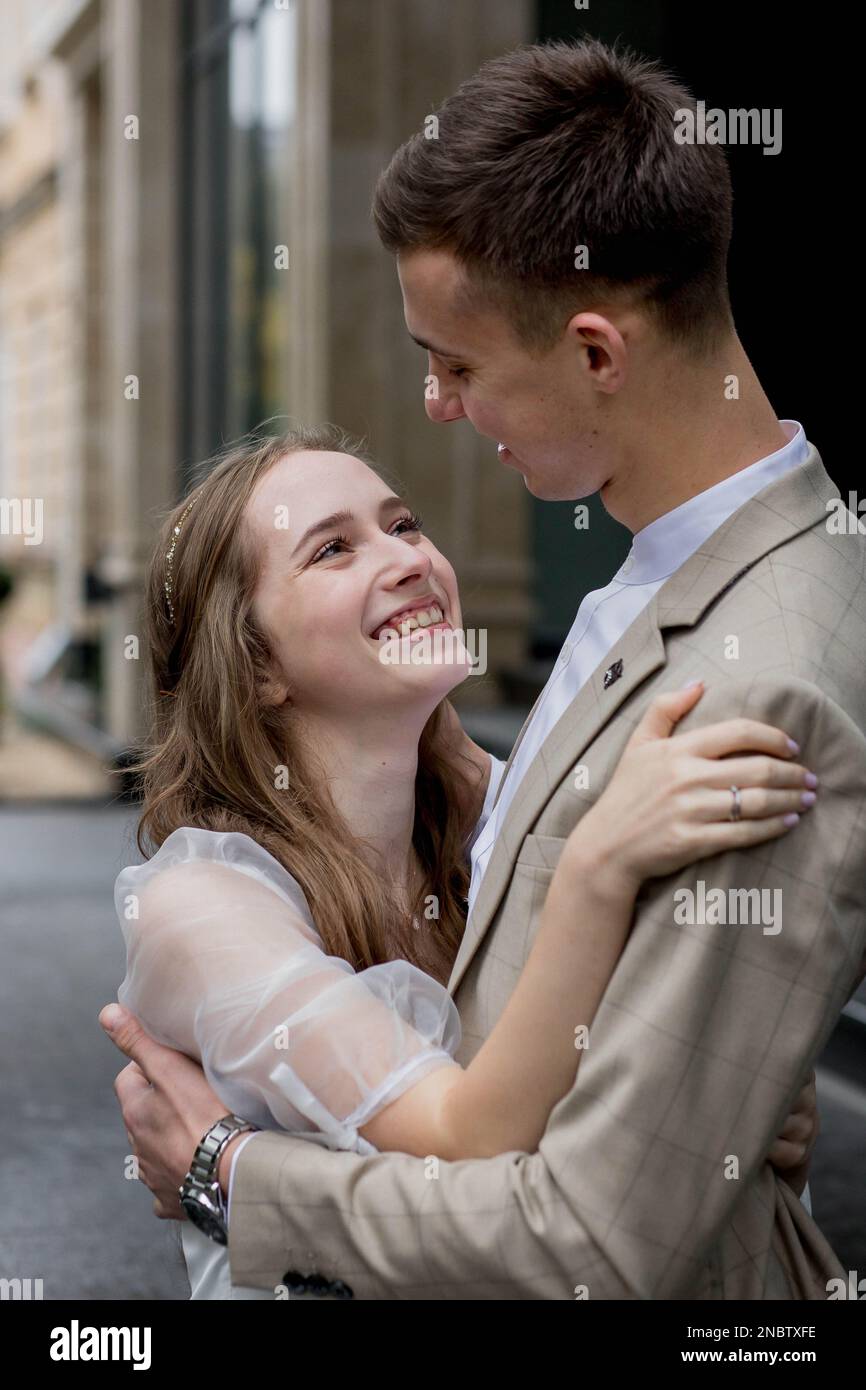 The bride looks at the groom with loving eyes. Smiling newlyweds look ...