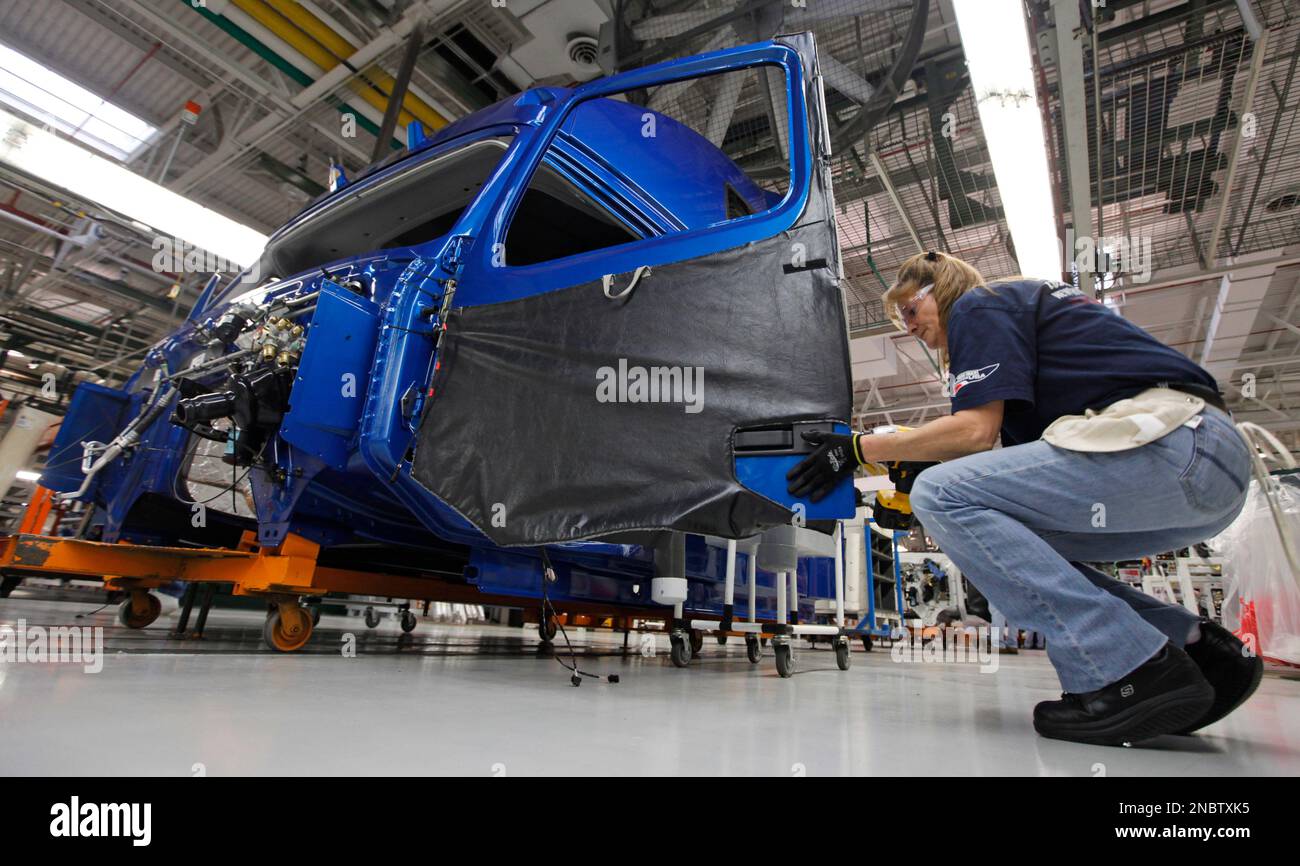 Shelby Corvin installs a door handle on a truck cab on the Volvo truck ...