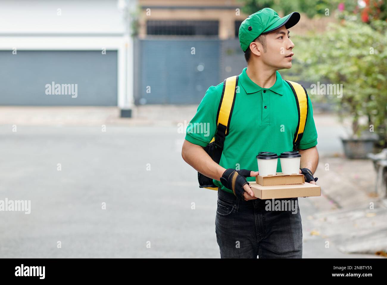 Courier in green uniform delivering lunch to customer Stock Photo - Alamy