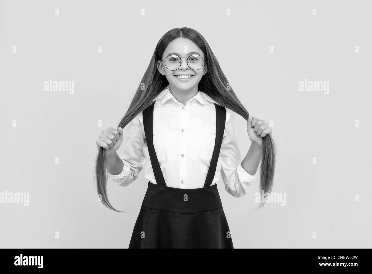cheerful kid hold long hair in school uniform and glasses for vision ...