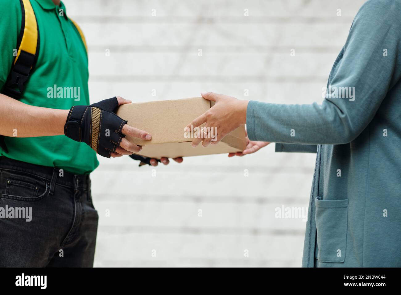 Delivery man giving cardboard package with food to female customer ...