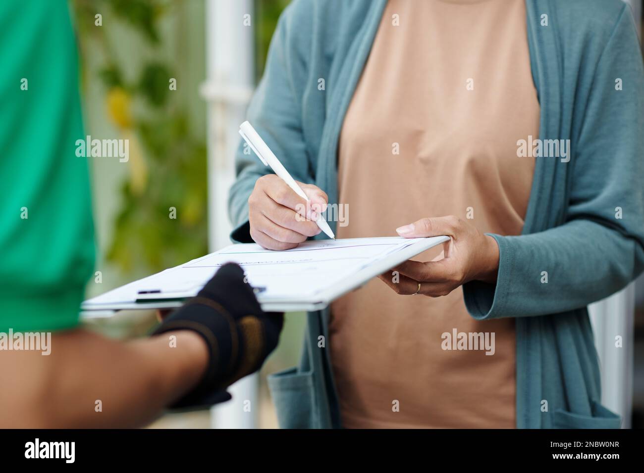 Customer signing document in hands of courier after receiving parcel ...