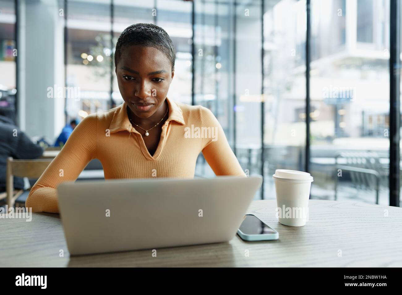 Young african woman freelancer working on laptop while sitting in ...
