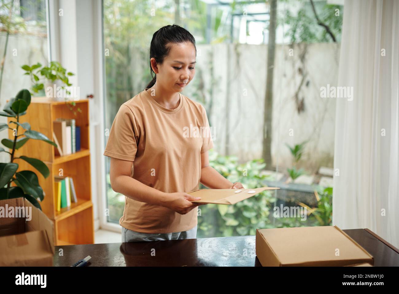 Woman opening paper envelop with important documents Stock Photo - Alamy