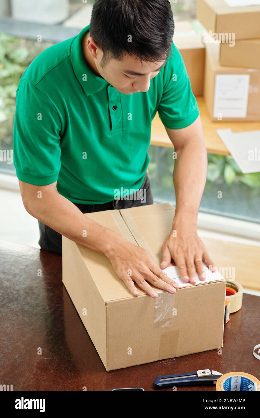 Post worker sticking piece of paper with address on cardboard box Stock ...