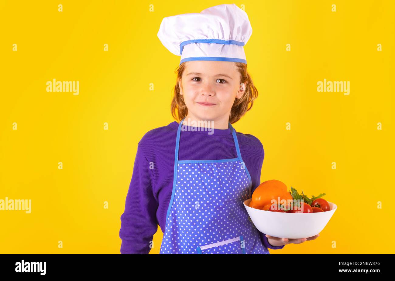 Kid cook hold plate with vegetables. Child chef cook, studio portrait ...