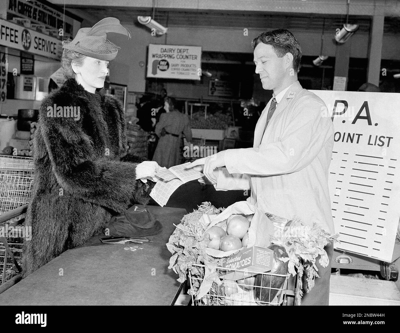 Mrs. Caven holds her new point ration book as the grocer indicates the ...