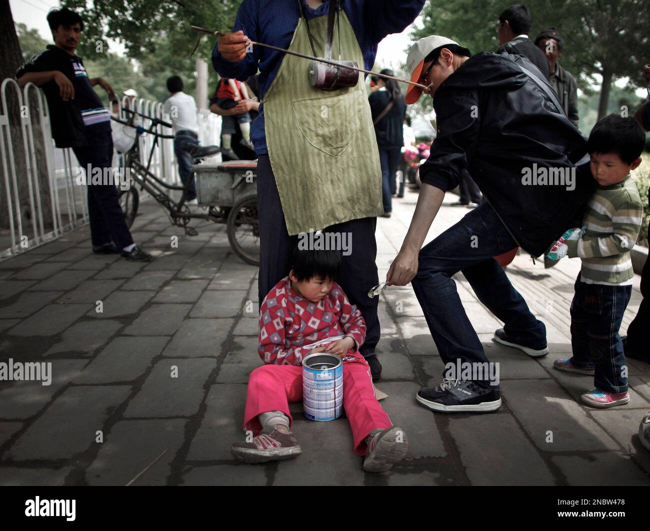 A tourist gives money to a child sit below a beggar playing with a ...