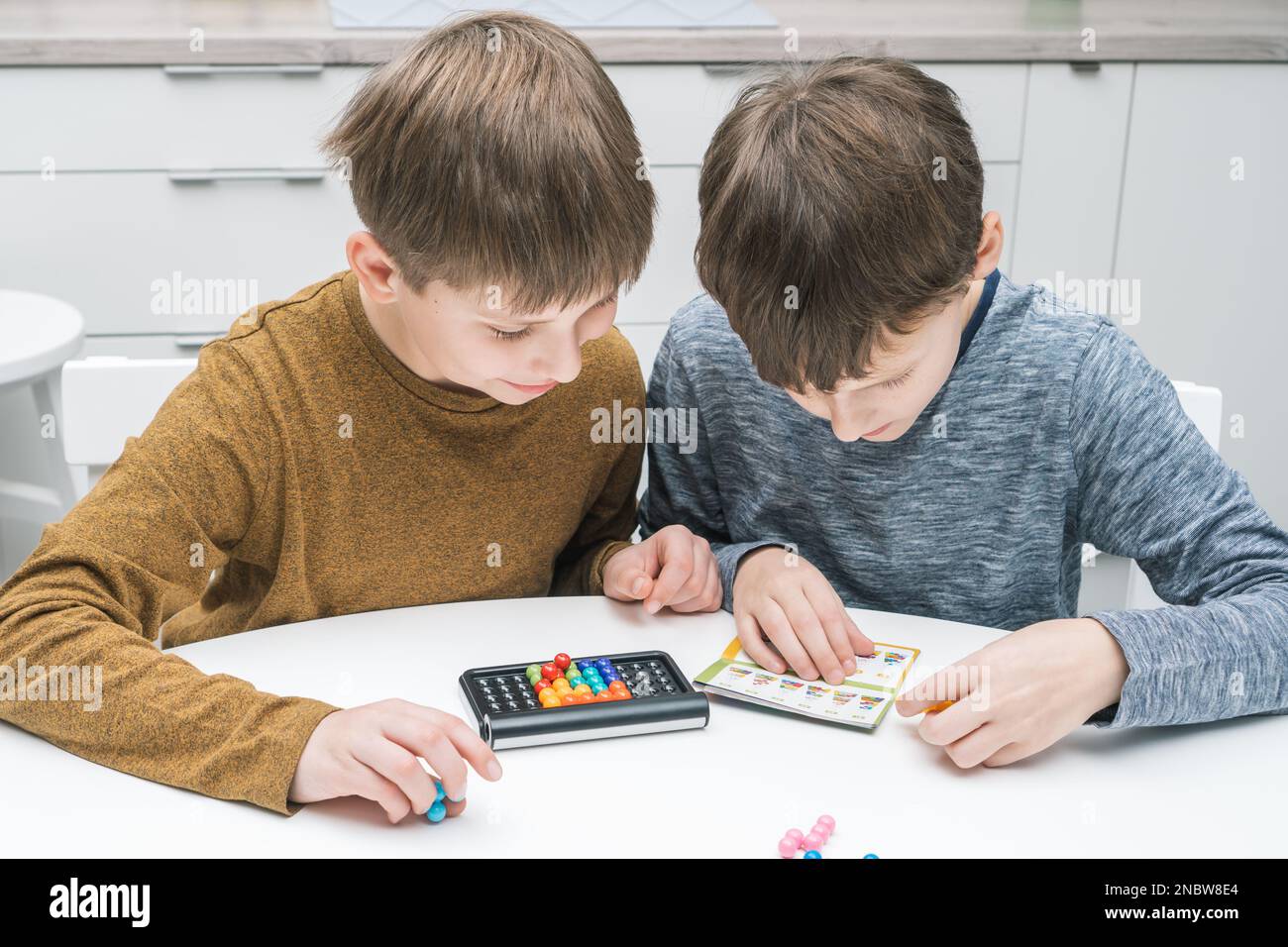 Happy schoolboys play toy constructor sitting at table. Children ...