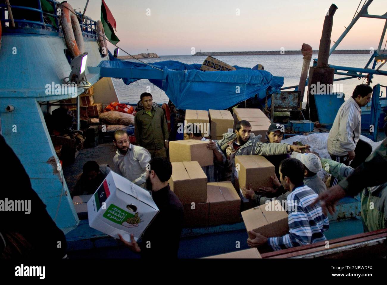 Libyan rebels load goods into a fishing boat before leaving Benghazi ...