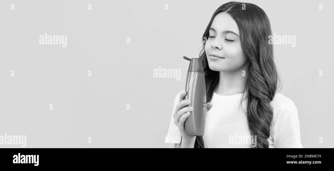 smiling teen girl with long hair smelling shampoo bottle, beauty ...