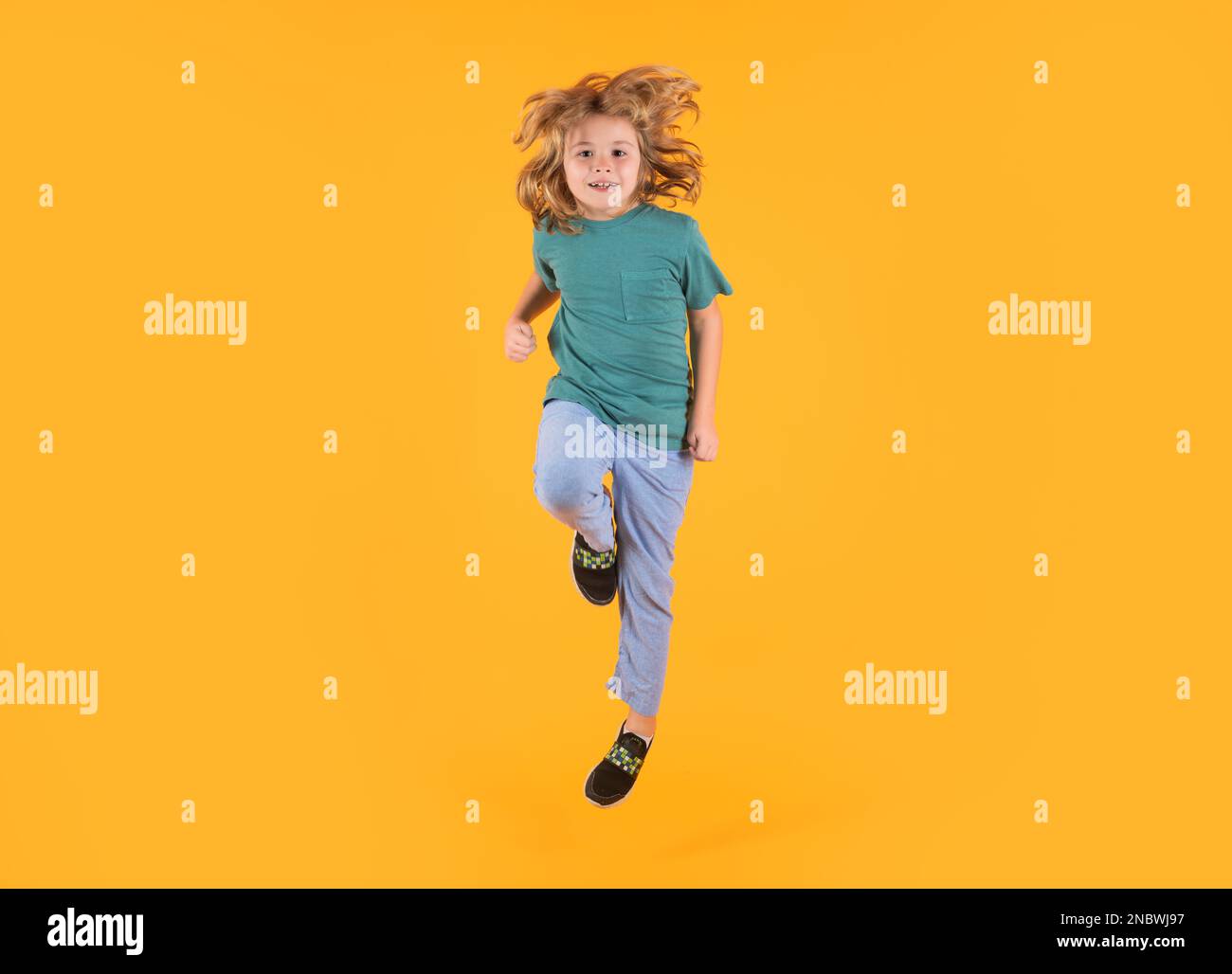 Energetic kid boy jumping and raising hands up on isolated studio ...