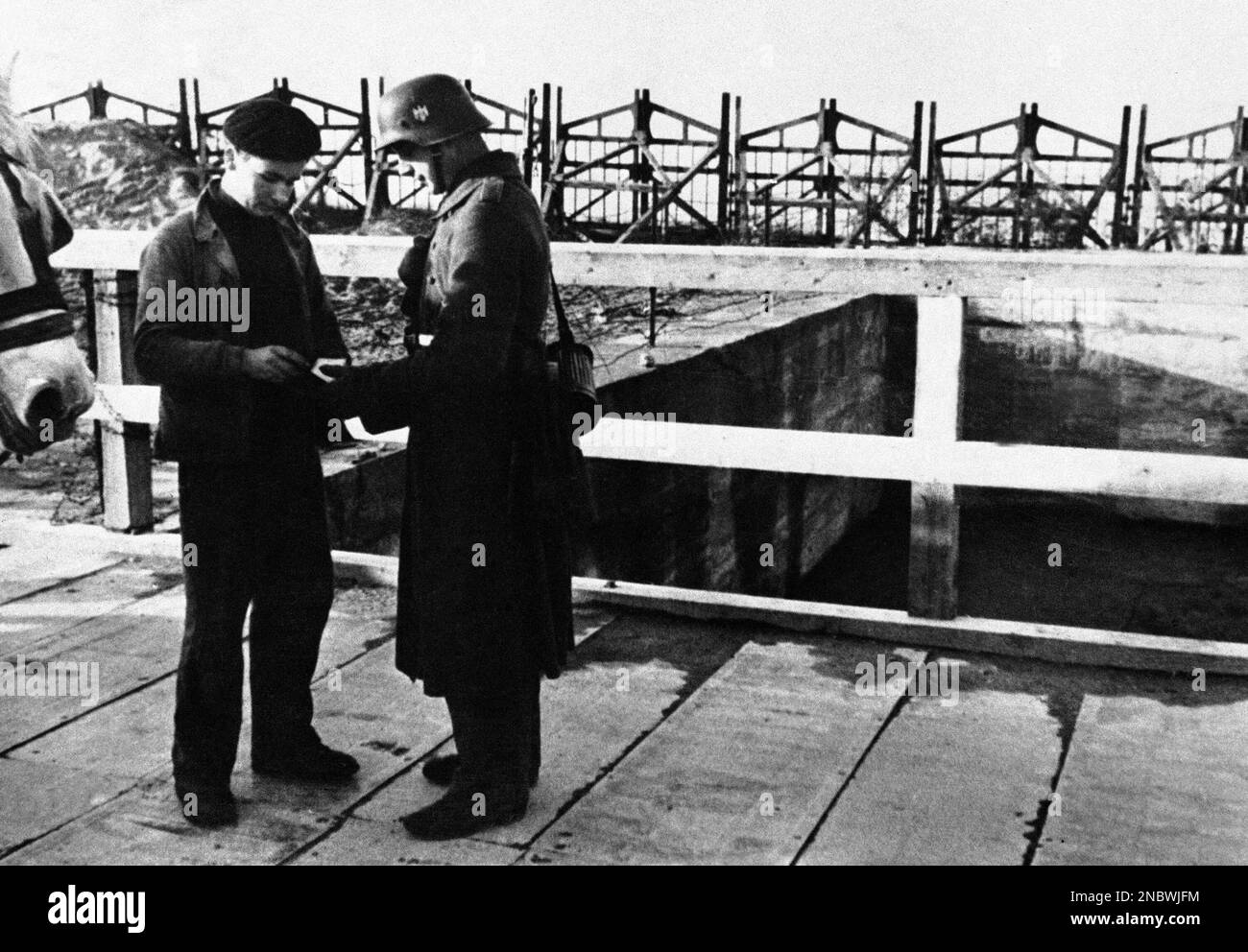 A German soldier checks the identification card of a civilian who works ...