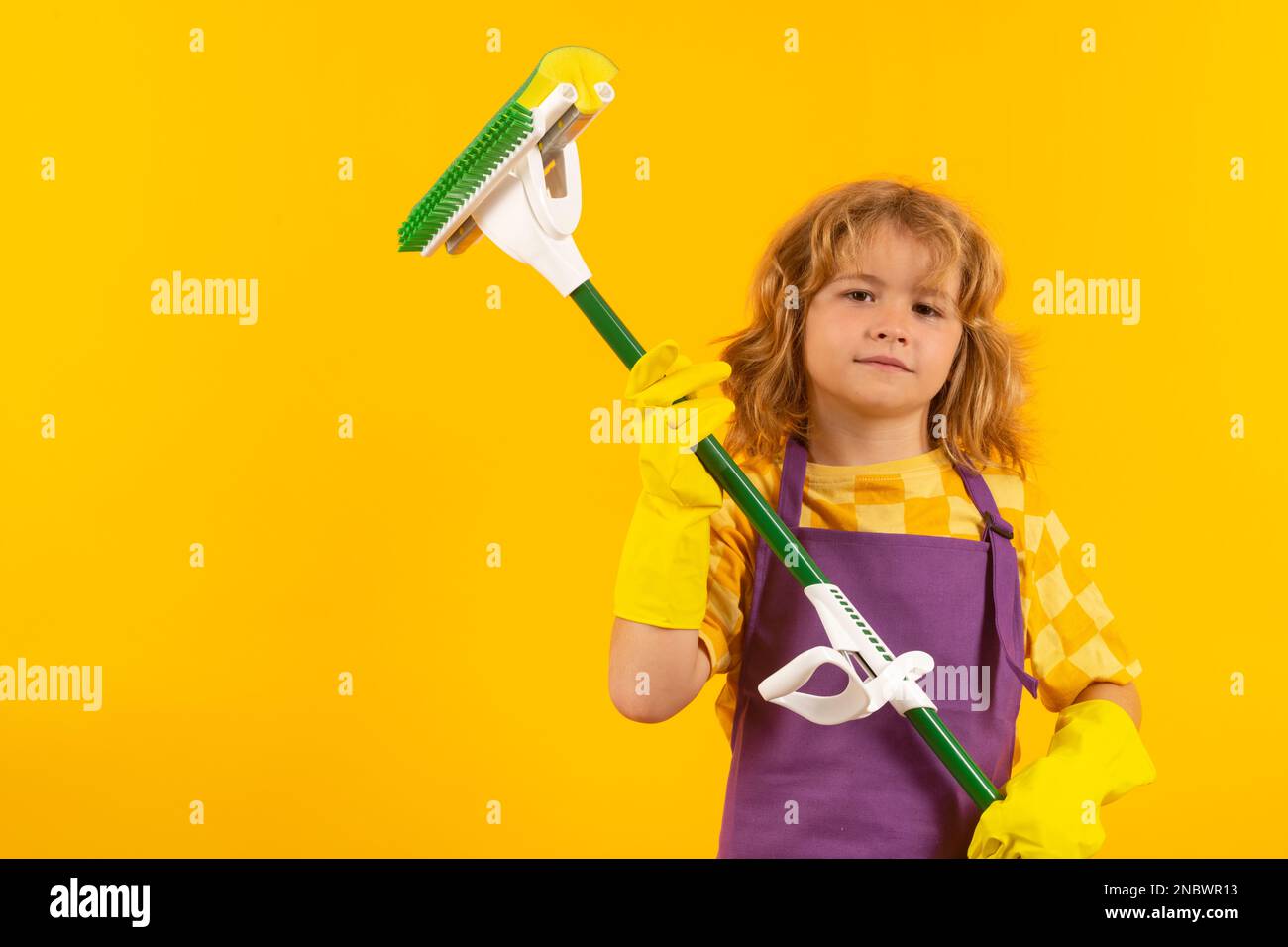 Child doing housework. Studio portrait of child use duster and gloves ...