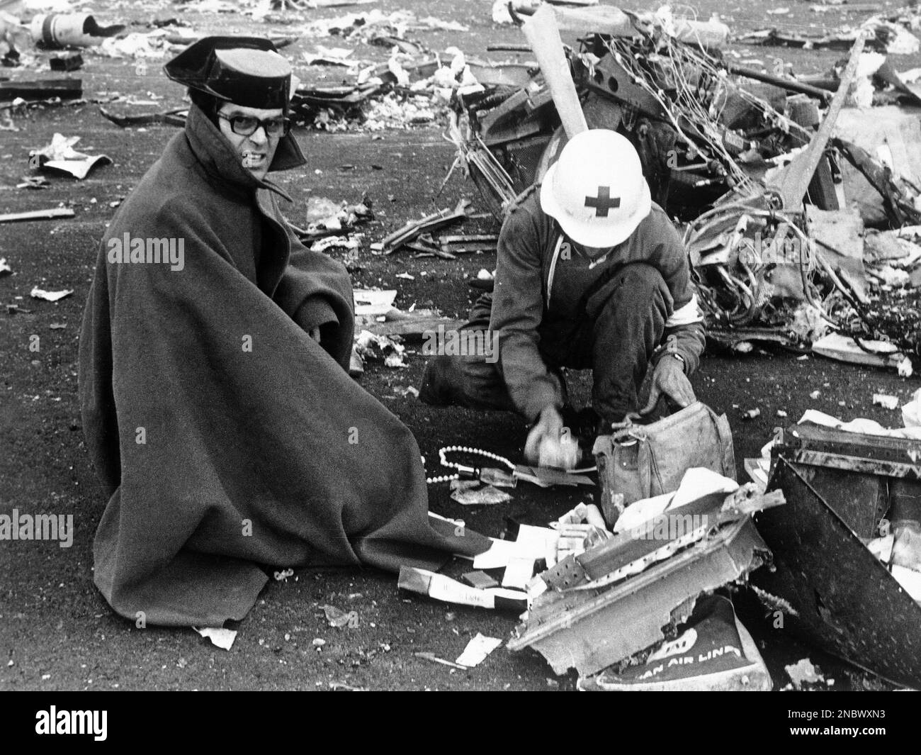 Watched by a Spanish Civil Guard, a Red Cross workersorts through ...