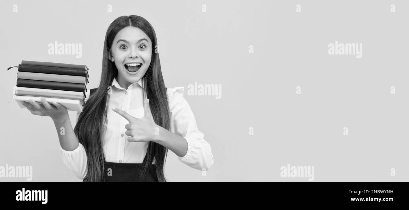 surprised teen girl in school uniform pointing finger on book stack ...