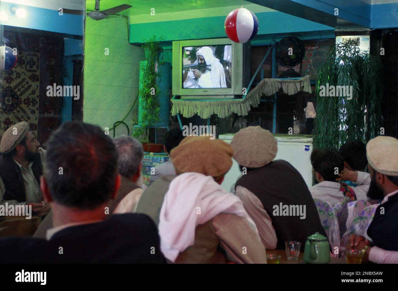 Afghan men watch television coverage announcing the killing of Al-Qaida ...