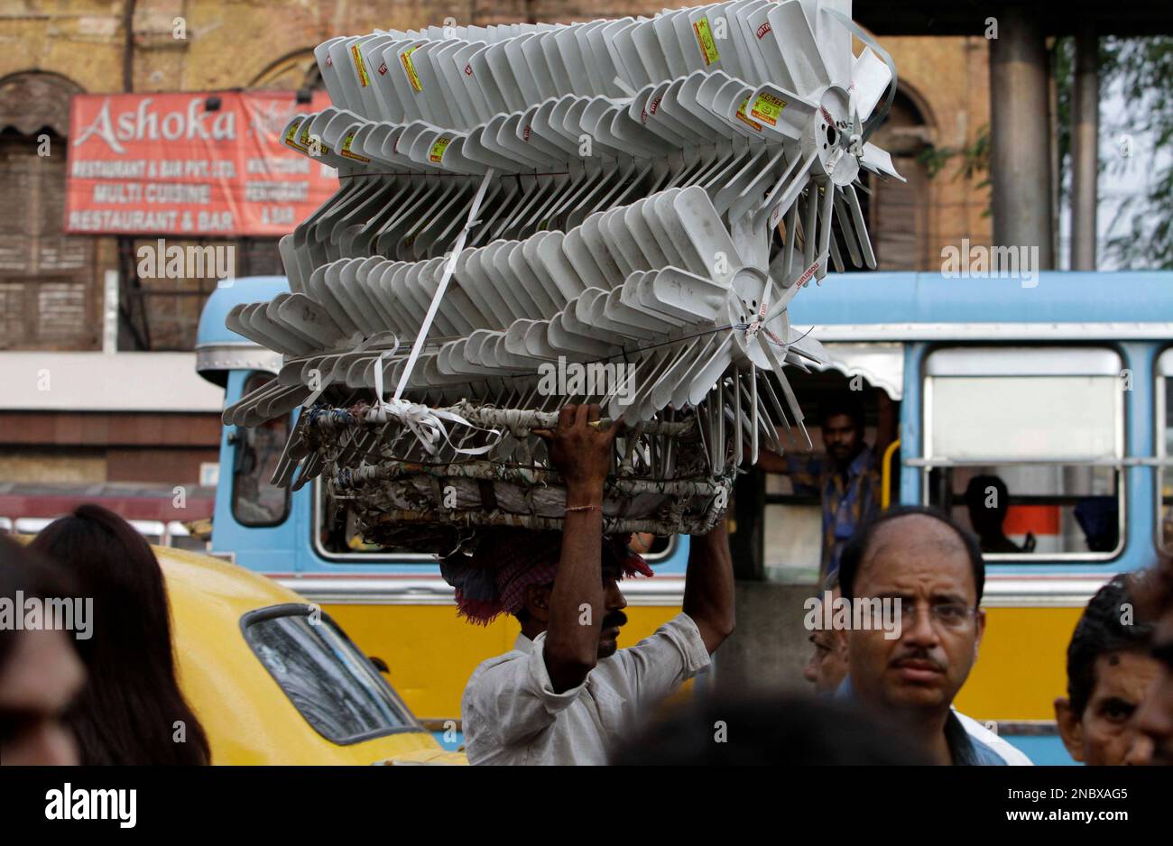 An Indian porter carries synthetic blades of exhaust fans for delivery ...