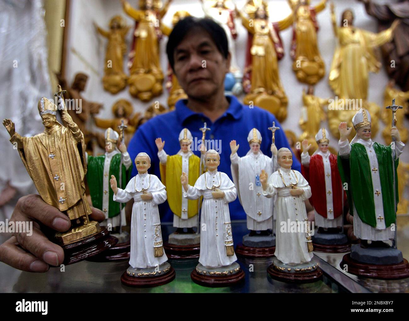 A religious store attendant displays different images of the late Pope ...