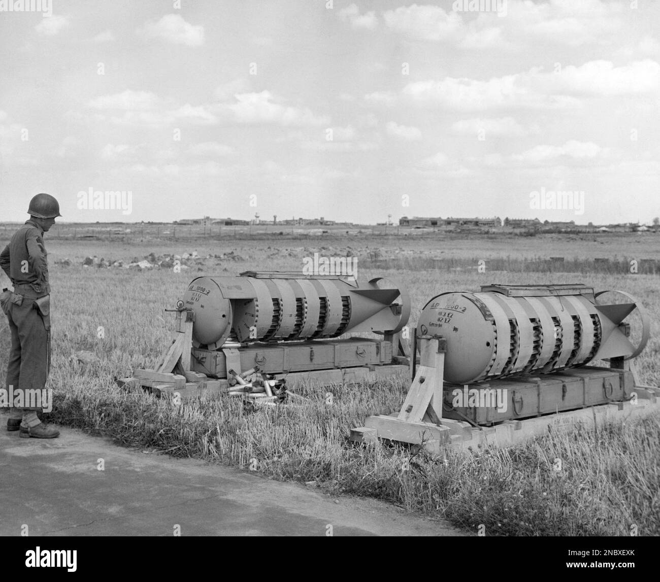 A GI looks at huge magnesium bombs along a runway of a captured German ...