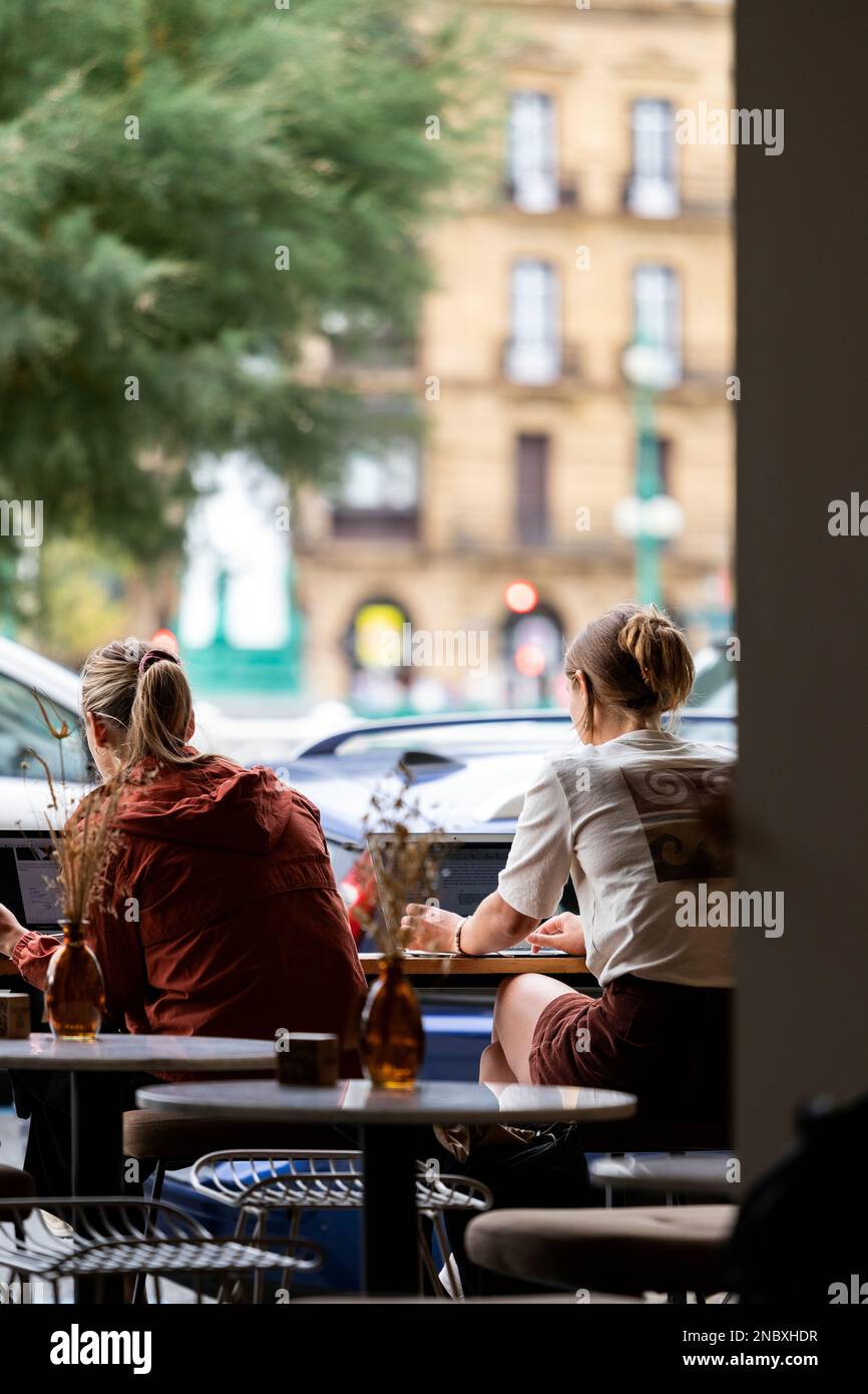 Two women sitting at a cafe working Stock Photo - Alamy