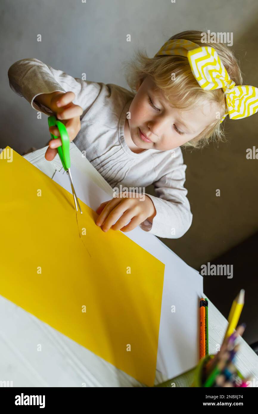 girl cuts out ornaments from colorful paper for crafting. Crafty girl ...