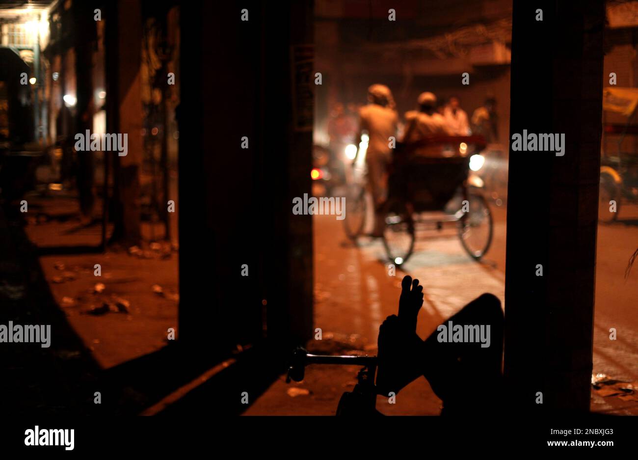 The feet of an Indian rickshaw puller are seen as he sleeps on his ...