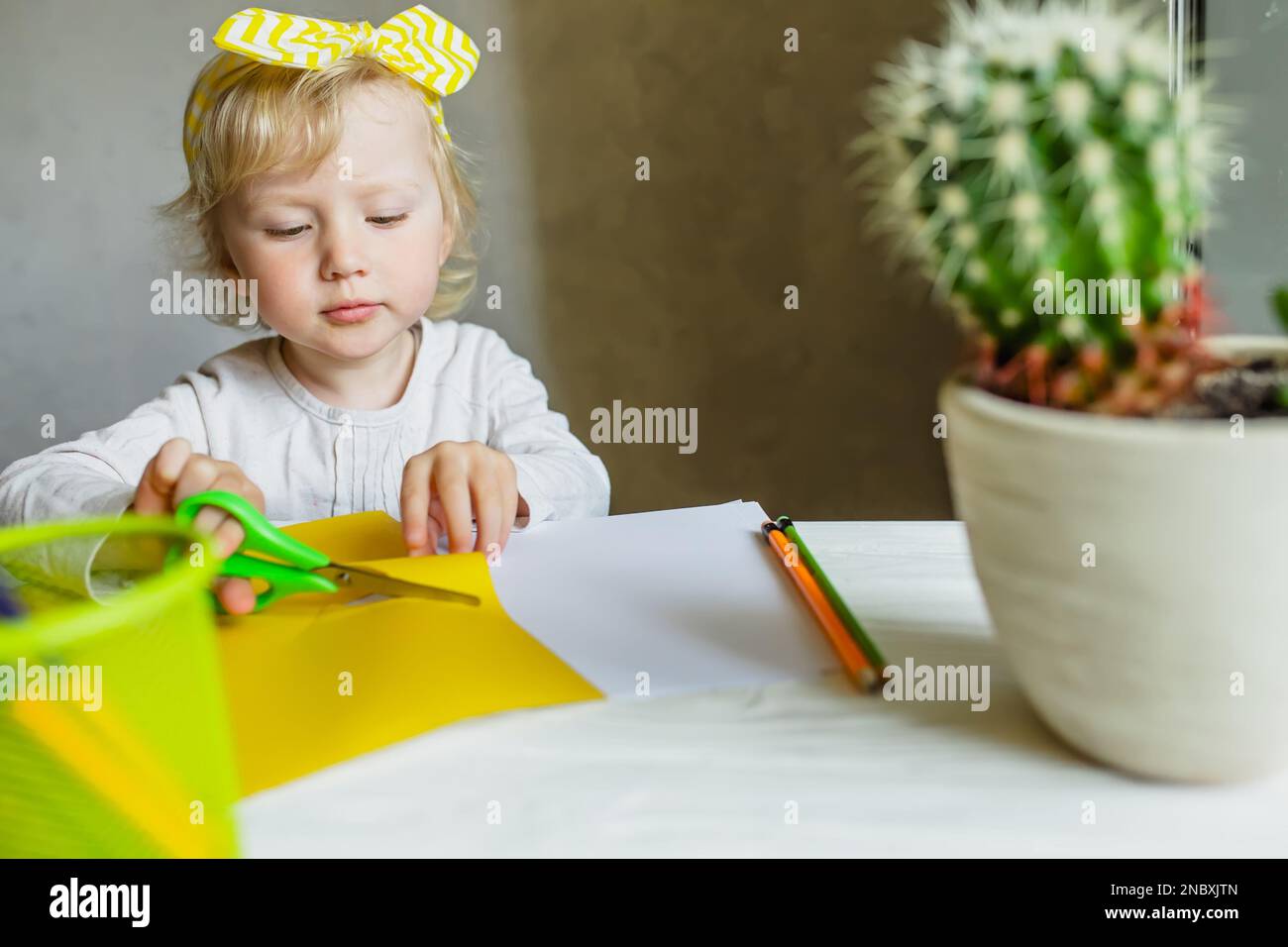 Caucasian girl cutting paper with scissors. School project for children ...