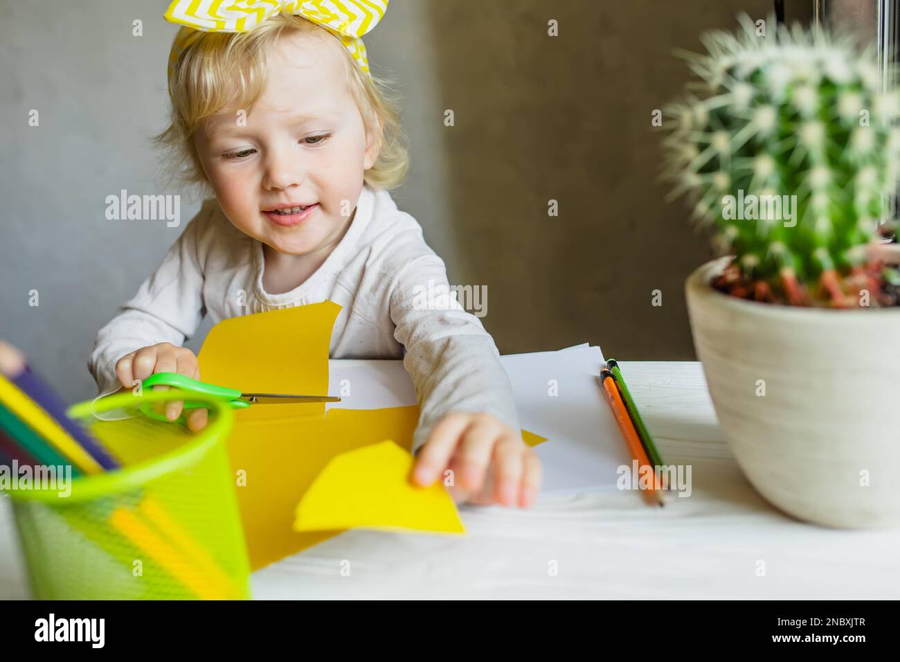 Little girl is cutting paper using scissors. Fine motor skills for ...
