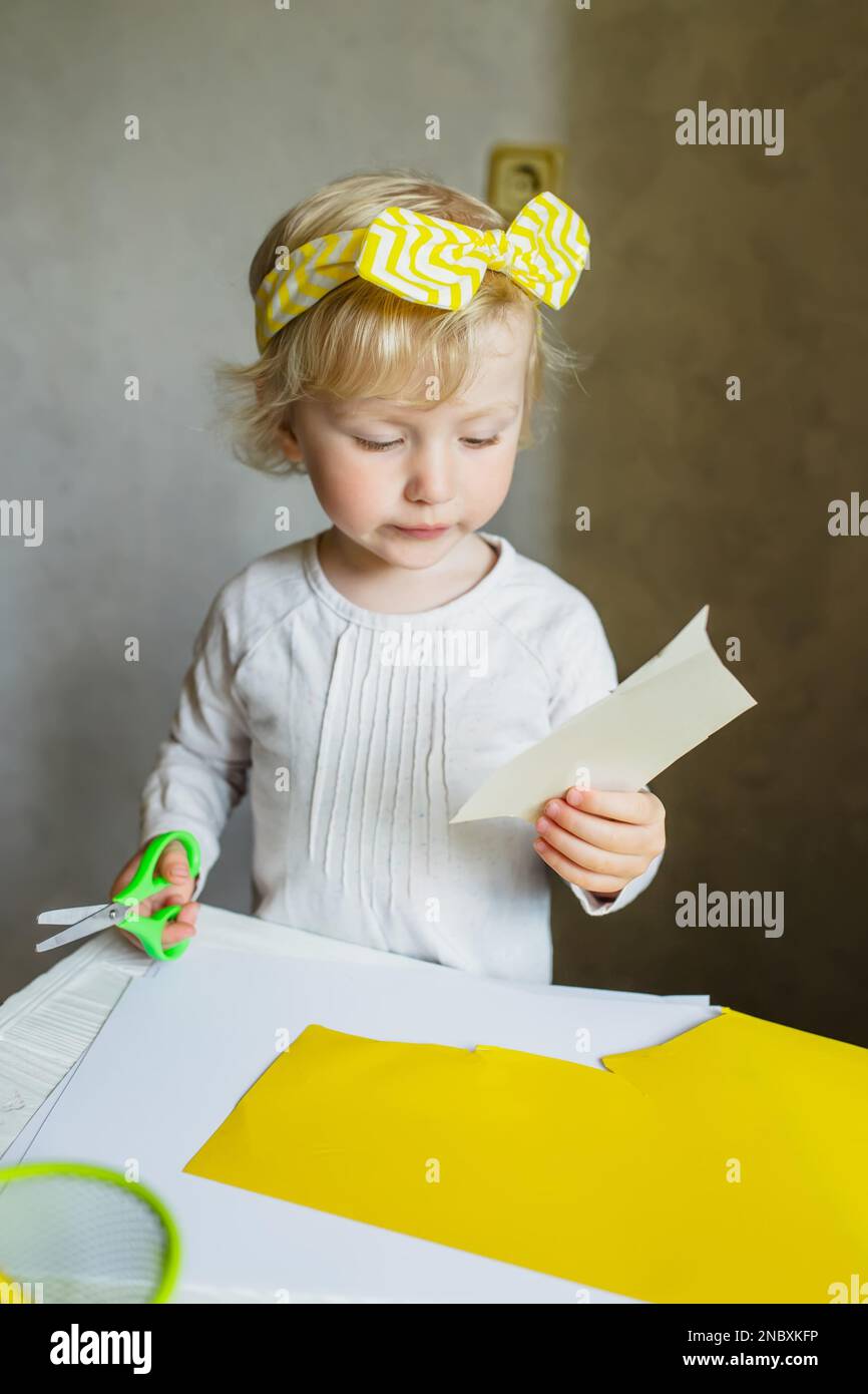 Portrait of a llittle girl is cutting color paper. School project for ...